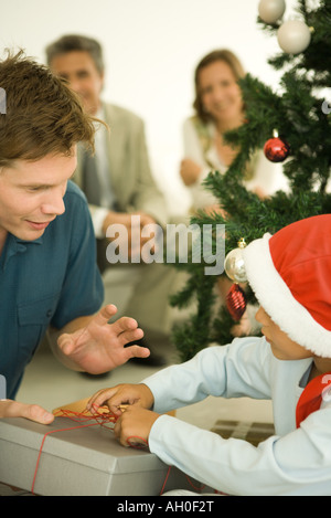 Time for presents. A boy and his dad sitting with a gift on Christmas ...