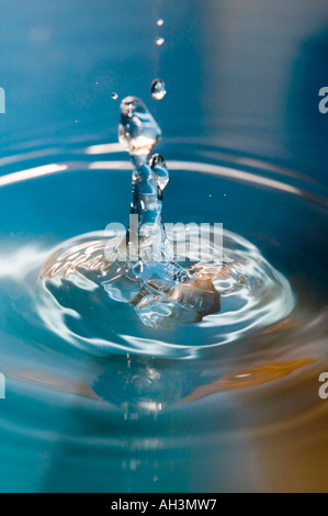 Water drop hitting the surface of water and rebounding with a colourful ...