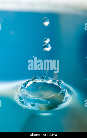 Water drop hitting the surface of water and rebounding with a colourful ...