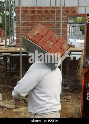 Close up of hod carrier with full load of facing bricks beside diesel ...