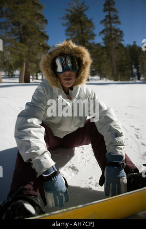 Tired snowboarder sitting on snow covered landscape while looking at ...