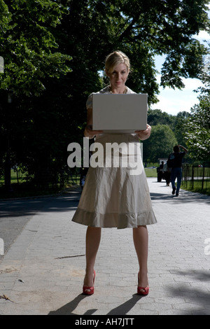 Young adult woman using a laptop and phone at a park table Stock Photo ...
