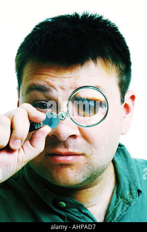 Man looks through magnifying glass at one hundred dollar bills hanging ...