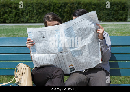young businessman hiding behind newspaper and sitting isolated on white ...