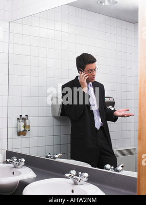 Man reflected in office washroom mirror doing up his tie Stock Photo ...