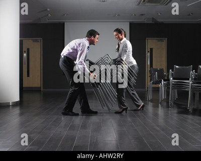 Man moving stack of chairs in empty presentation room Stock Photo - Alamy
