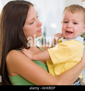 Young mother hugging crying and sad daughter, sitting on bed with white ...