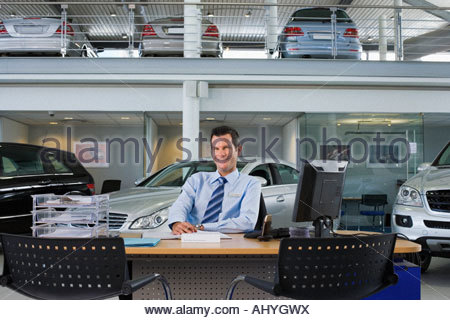 A new car salesman does the paperwork at a desk to complete a Stock ...