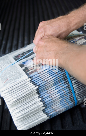 Newspaper carrier lifting a bundle of newspapers Stock Photo - Alamy