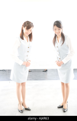 Two young Japanese women bowing to each other in greeting Stock Photo ...