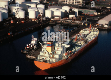 Oil tanker ship moored at marine terminal with fuel storage tanks and ...