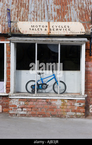 Brand new bicycles on show in neglected shop window of bike shop ...