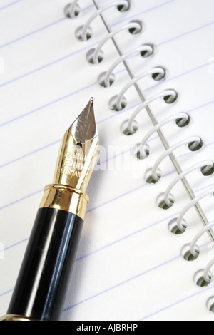 Fountain pen on a notebook. Black ink splash. Wooden table. Copy space ...