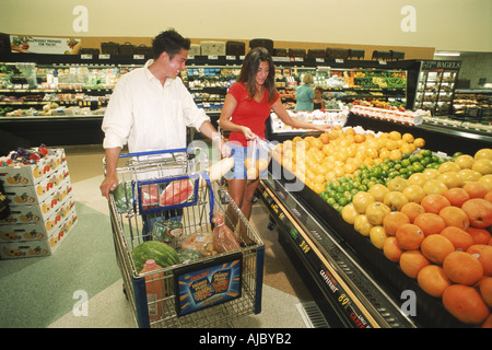 Man pushing shopping cart through supermarket aisle while buying ...