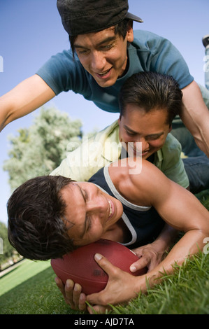 Group of friends playing soccer and fighting over football in grass at ...