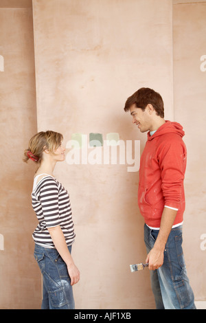 Smiling young couple choosing brush for house decoration in paint ...