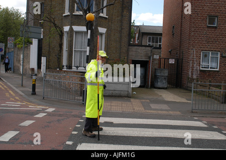 School crossing patrol man with stop sign and 'people crossing' sign ...