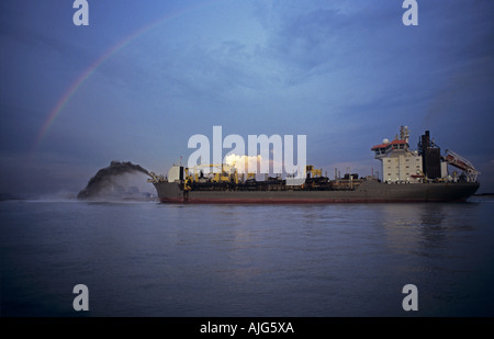 Dredger rainbowing or discharging cargo of sand for land reclamation ...