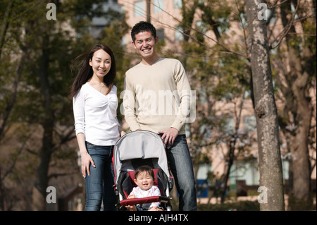 A young family with a baby in a stroller admire a view of a river while ...