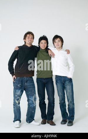 Full length portrait of three young men drinking beer outdoors in ...