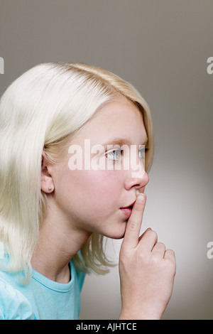 Girl putting a finger to her lips Stock Photo - Alamy