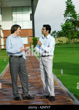 Two friends standing on the pathway and looking at the wavy ocean on ...