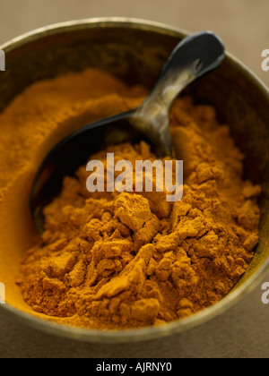 Vibrant orange turmeric powder in white ceramic bowl, garlic, red chili ...