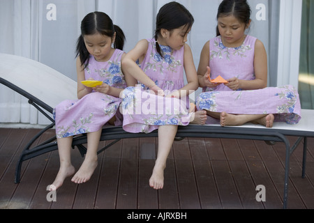 Three girls making paper boats Stock Photo - Alamy