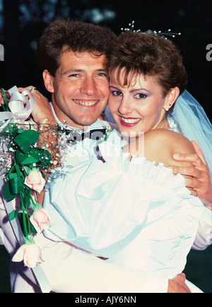 Young happy wedding couple posing outdoors in garden or in the park ...