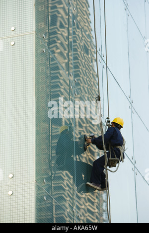 Window washers hanging from ropes on outside of modern curved ...
