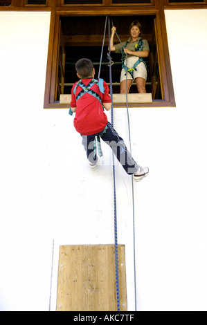 A girl abseiling down a climbing wall. The origin of the abseil is ...