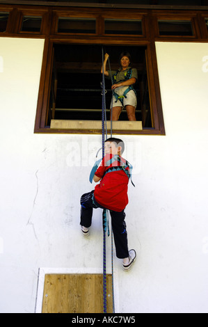 A girl abseiling down a climbing wall. The origin of the abseil is ...
