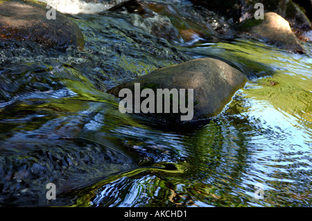 River flowing over submerged ridge of rock creating abstract shapes ...
