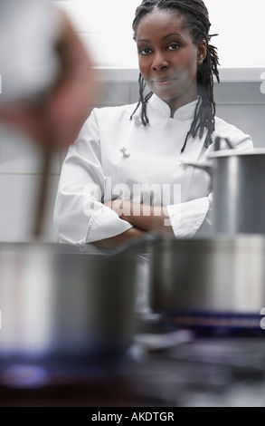 Smiling female chef in black uniform preparing vegetable salad in ...