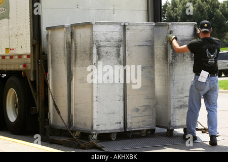 Truck driver man handling metal containers on a delivery to a retail ...