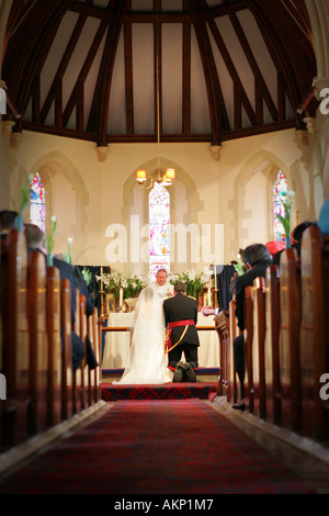 Bride and groom kneel at altar during typical catholic wedding ceremony ...
