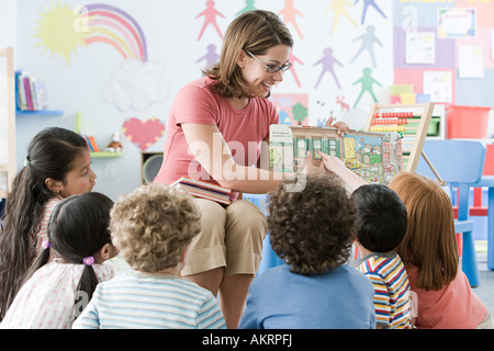 African American male preschool teacher reading a book to his Stock ...