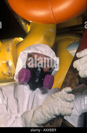 Asbestos removal. Worker in protective clothing removing asbestos from ...