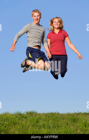 TWO YOUNG COUPLES JUMPING IN EXUBERANCE AGAINST A WHITE BACKGROUND ...