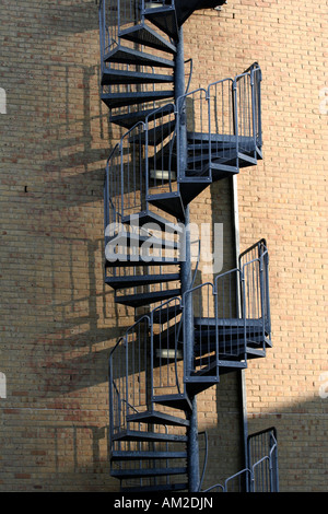 External metal spiral staircase on an orange building facade next to ...