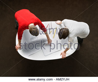 Two people leaning over a table laid outside with a white cloth and a ...