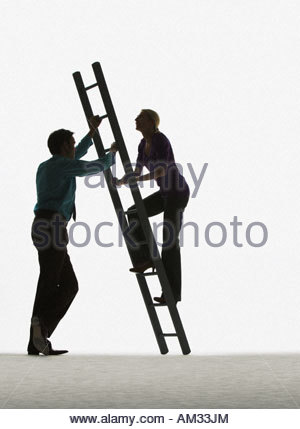 Young woman helping friend to climb up the rock. Two young females ...