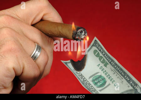 lighting a cigar with a 100 dollar bill in a show of extravagance Stock ...