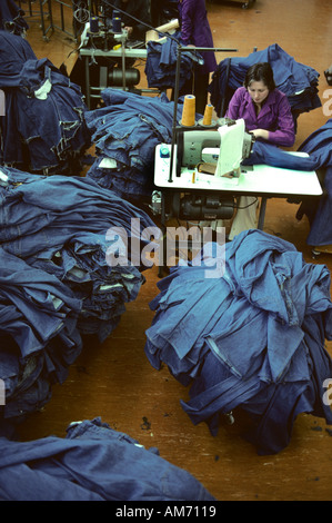 A garment worker at work on a sewing machine inside a garment factory ...