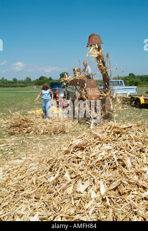 Husband and wife farmers thrash corn in a antique threshing machine ...