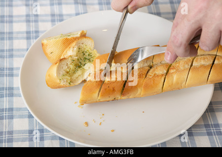 hand cutting slice of garlic bread with knife Stock Photo - Alamy