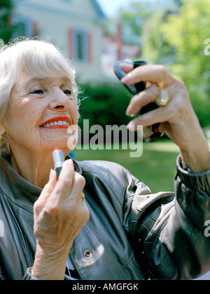Senior woman applying lipstick and laughing Stock Photo - Alamy