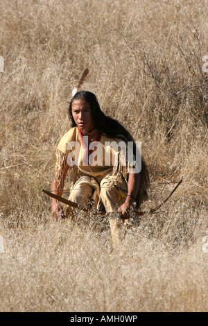 A Native American Indian boy crouching in the dead grasses hunting game ...