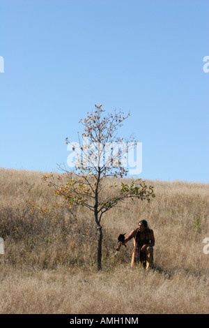A Native American Indian man crouching in the dead grasses hunting game ...