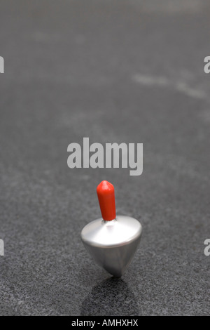 spinning top on a wet grey stone paver Stock Photo - Alamy